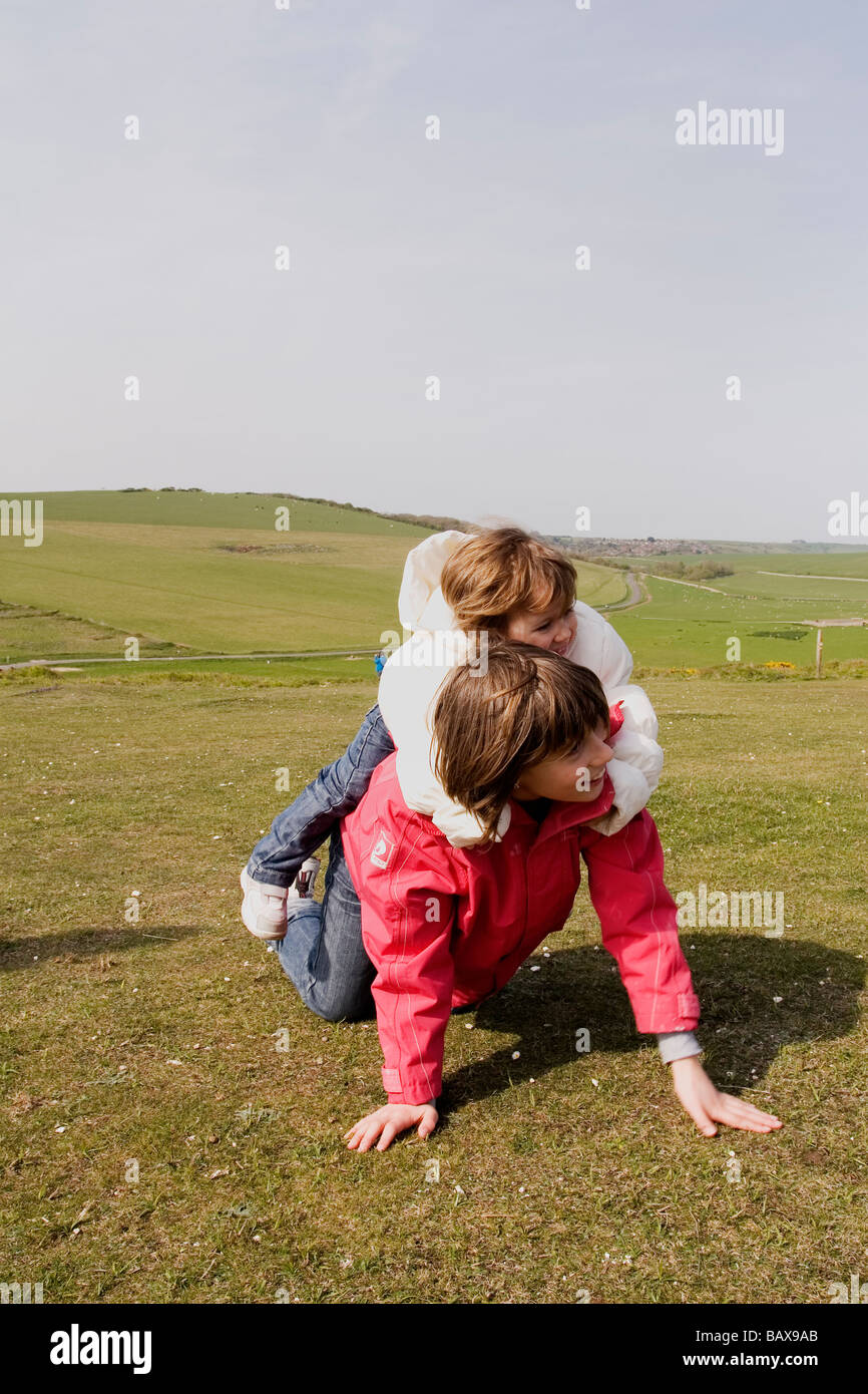 sisters play piggyback in field Stock Photo - Alamy