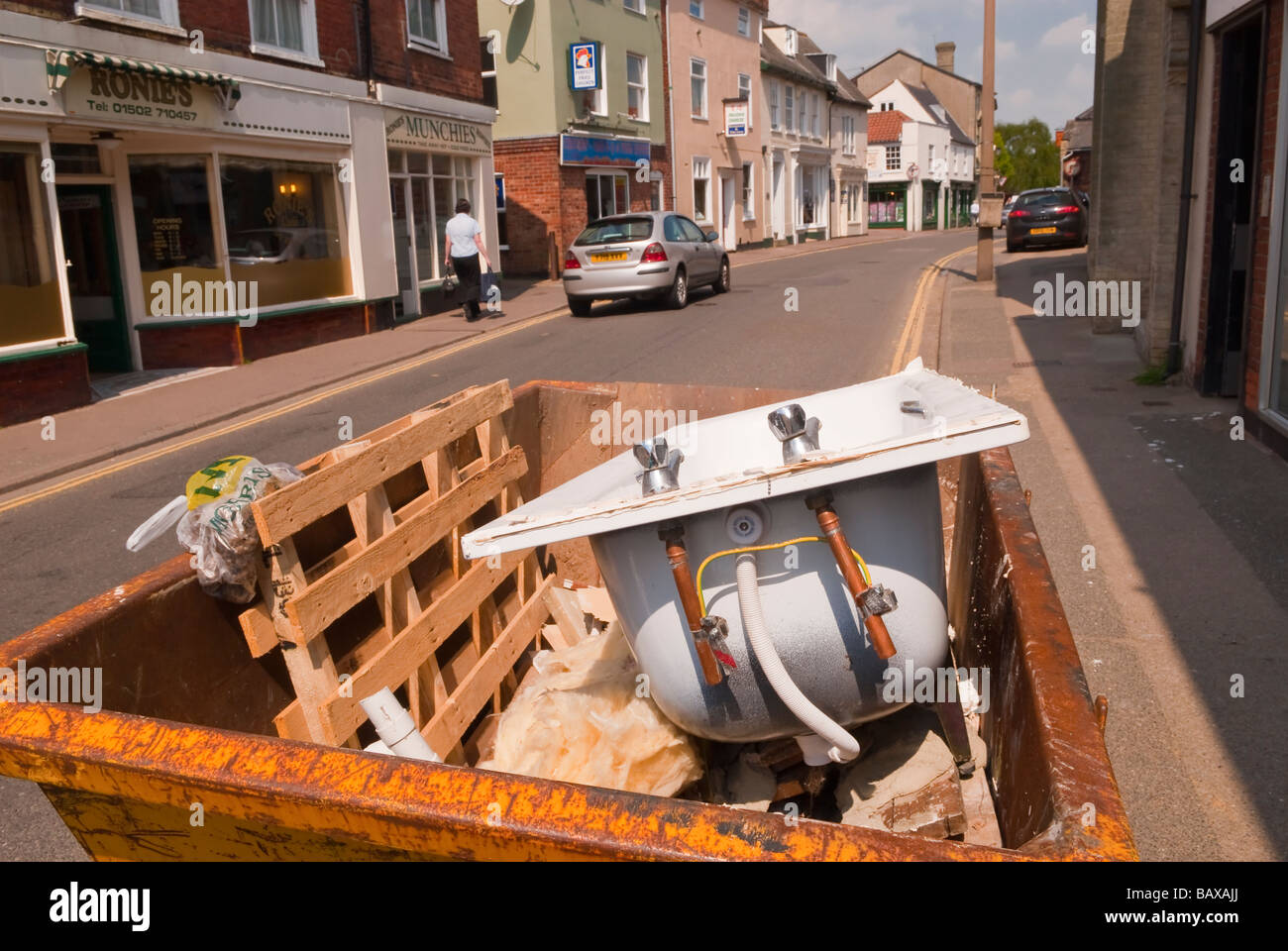 A rubbish skip situated in the road in a uk town filled with building ...