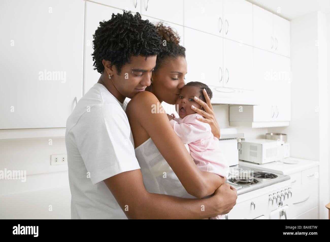 African parents hugging baby in kitchen Stock Photo - Alamy