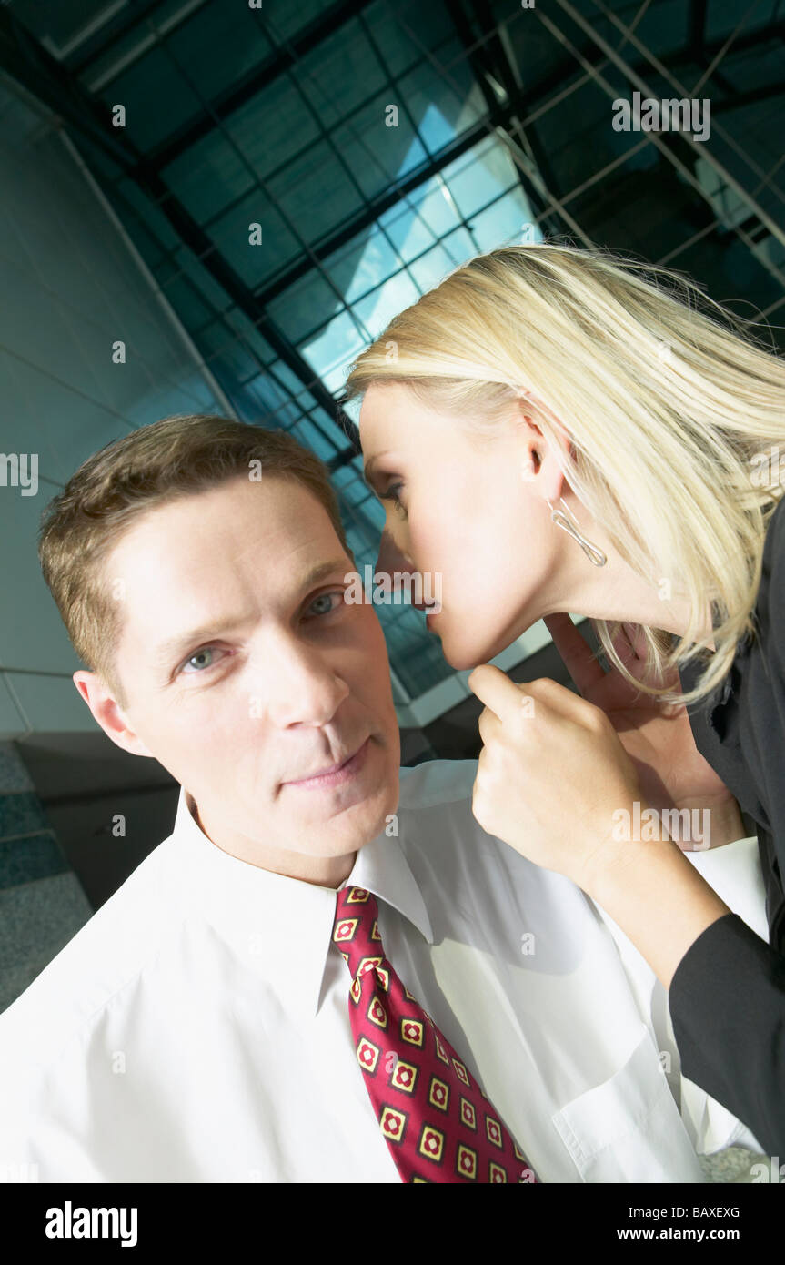 Businesswoman telling businessman a secret Stock Photo - Alamy