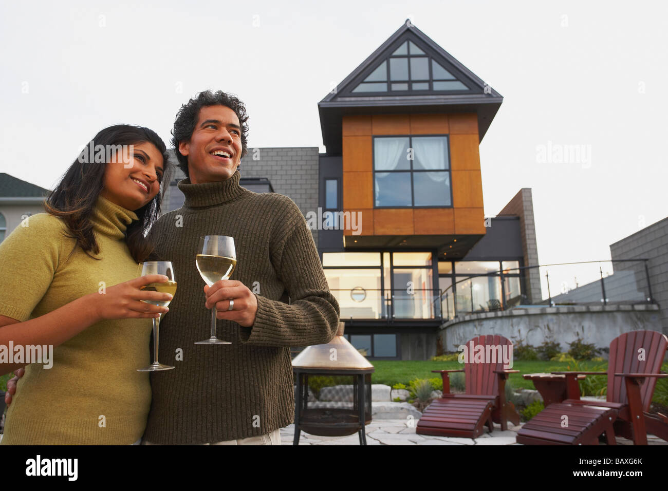 Couple holding wine in front of house Stock Photo - Alamy