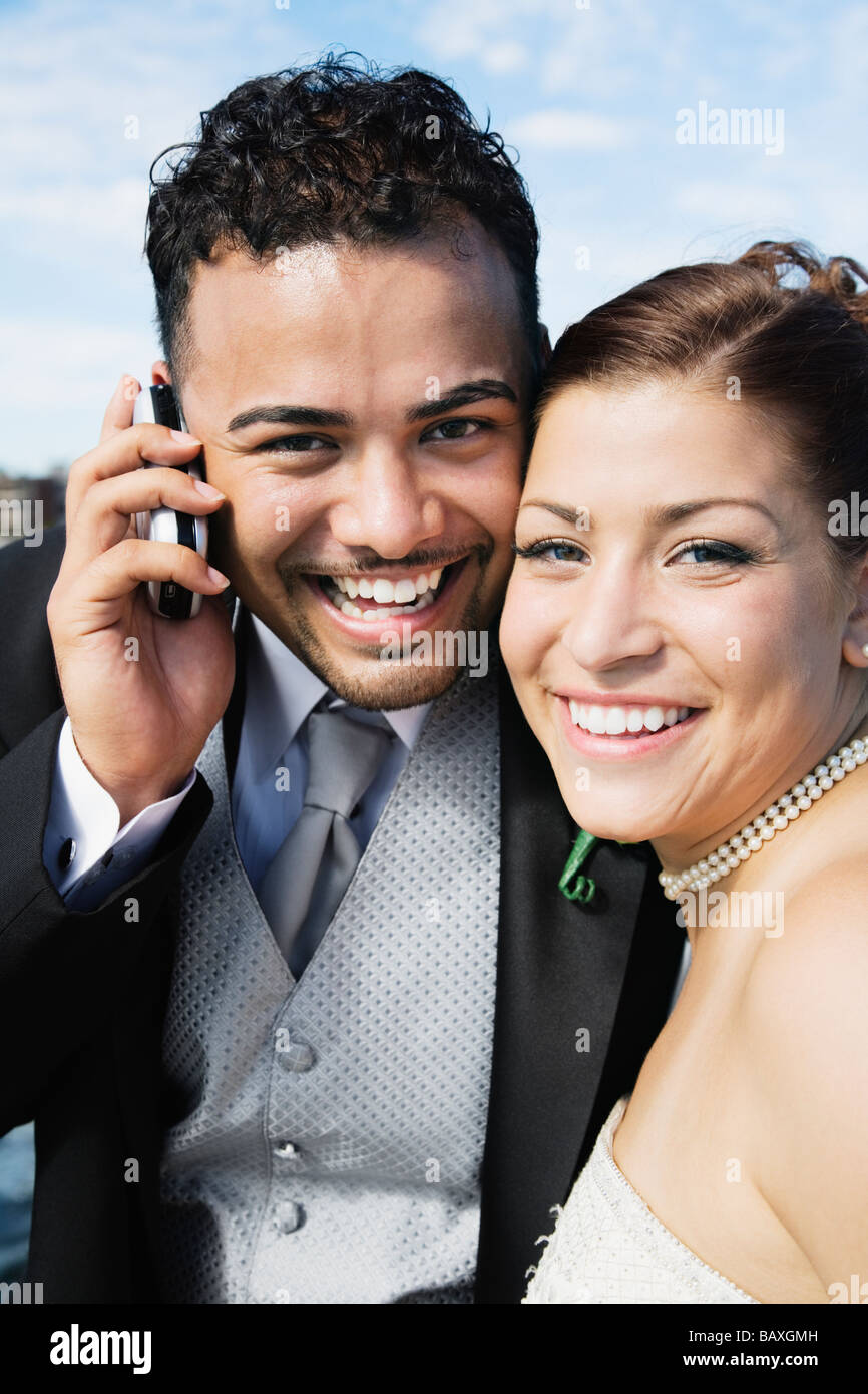 Multi-ethnic bride and groom with cell phone Stock Photo - Alamy
