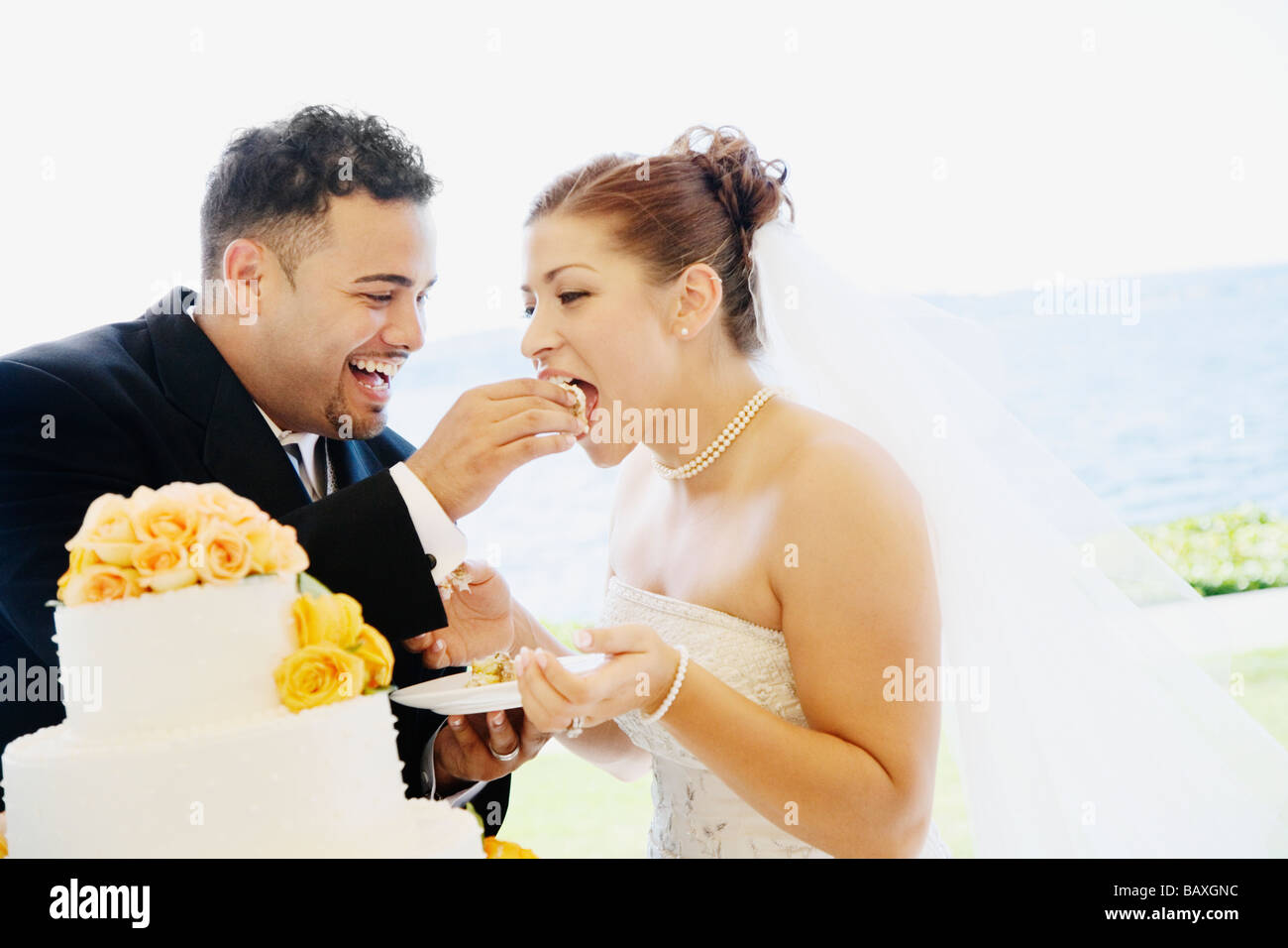 Multi-ethnic bride and groom eating cake Stock Photo - Alamy