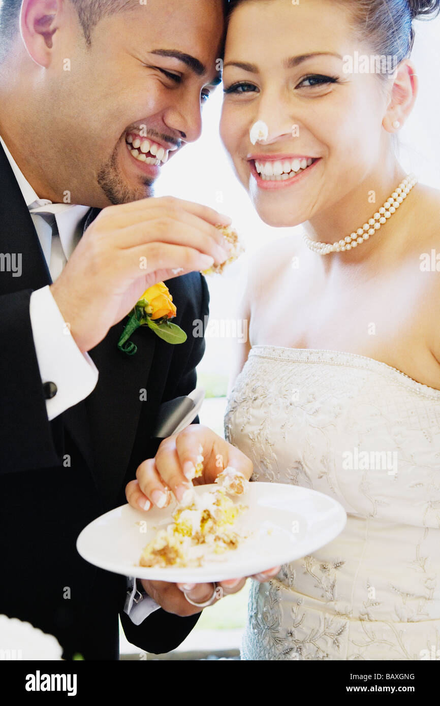 Multi-ethnic bride and groom eating cake Stock Photo - Alamy