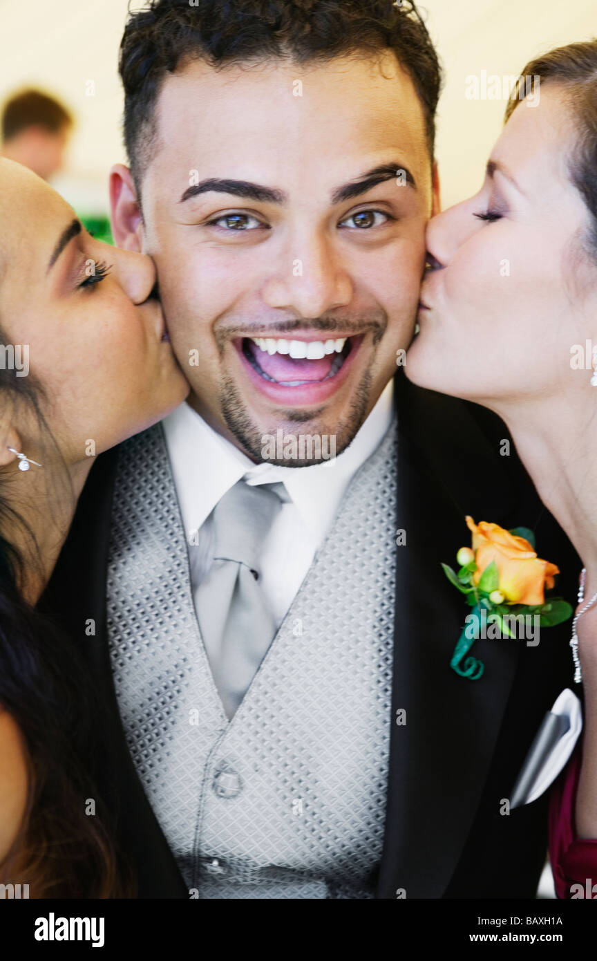 Groom being kissing by two women Stock Photo - Alamy