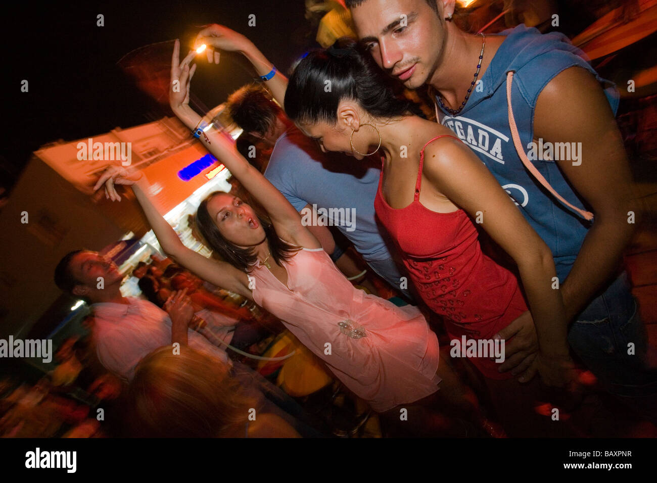 A group of young people dancing in front of a club, bar, nightlife ...