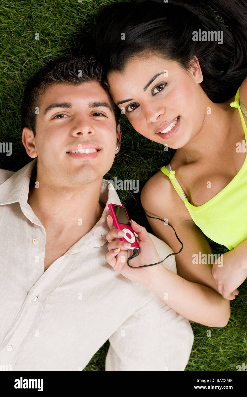 Young couple listening music on a mp3 player while relaxing outdoor ...
