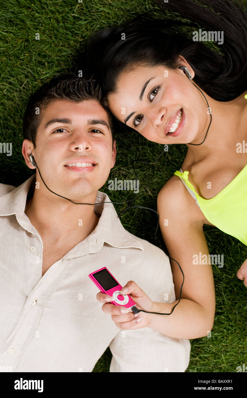 Young couple listening music on a mp3 player while relaxing outdoor ...