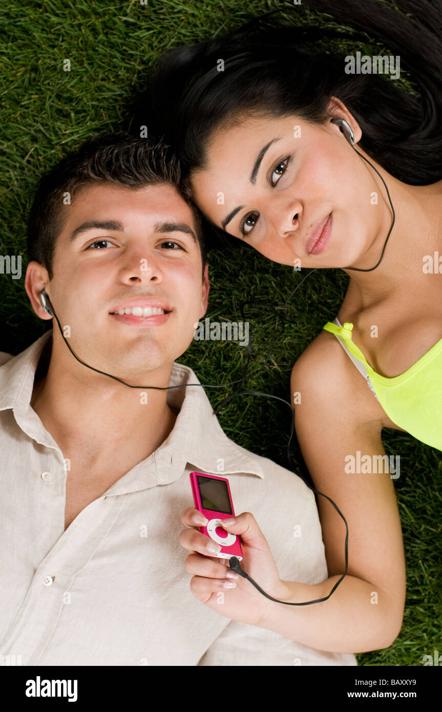 Young couple listening music on a mp3 player while relaxing outdoor ...