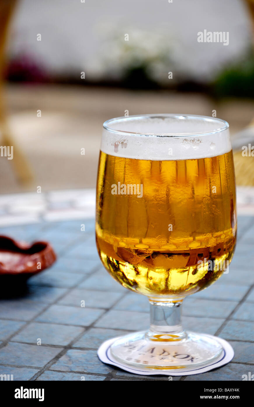 Close-up of a glass of cold beer on a stone top table on an outside ...