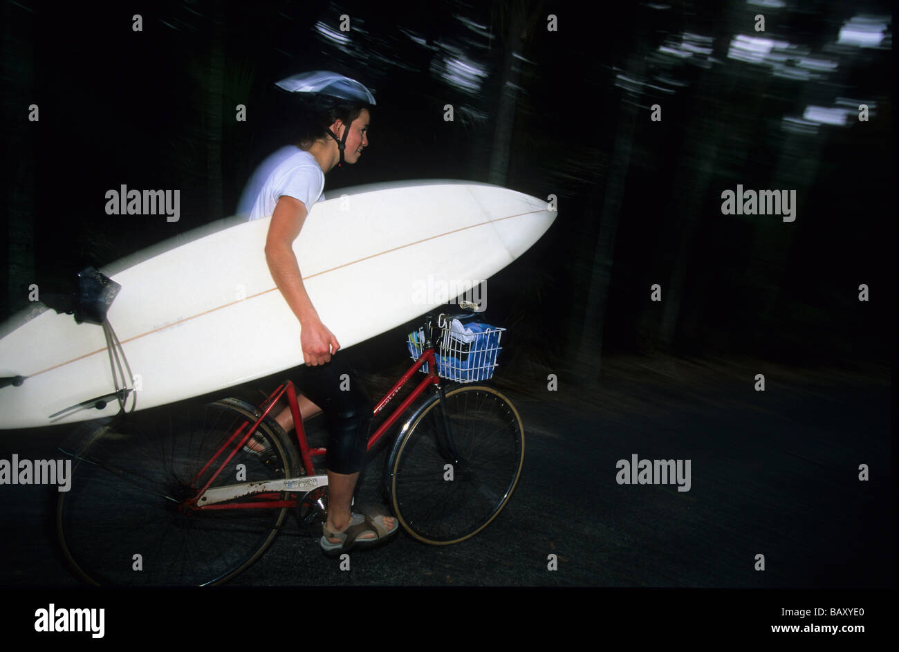 A surfer carrying his surfboard by bicycle, Lord Howe Island, Australia ...