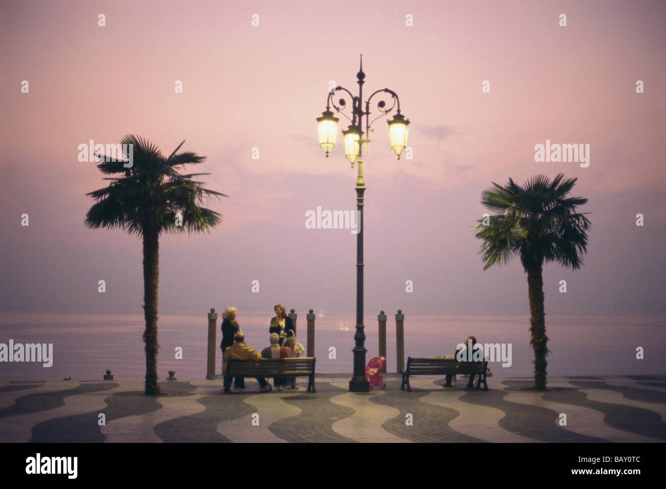 People sitting on benches at Garda Lake promenade, Lazise, Verona ...