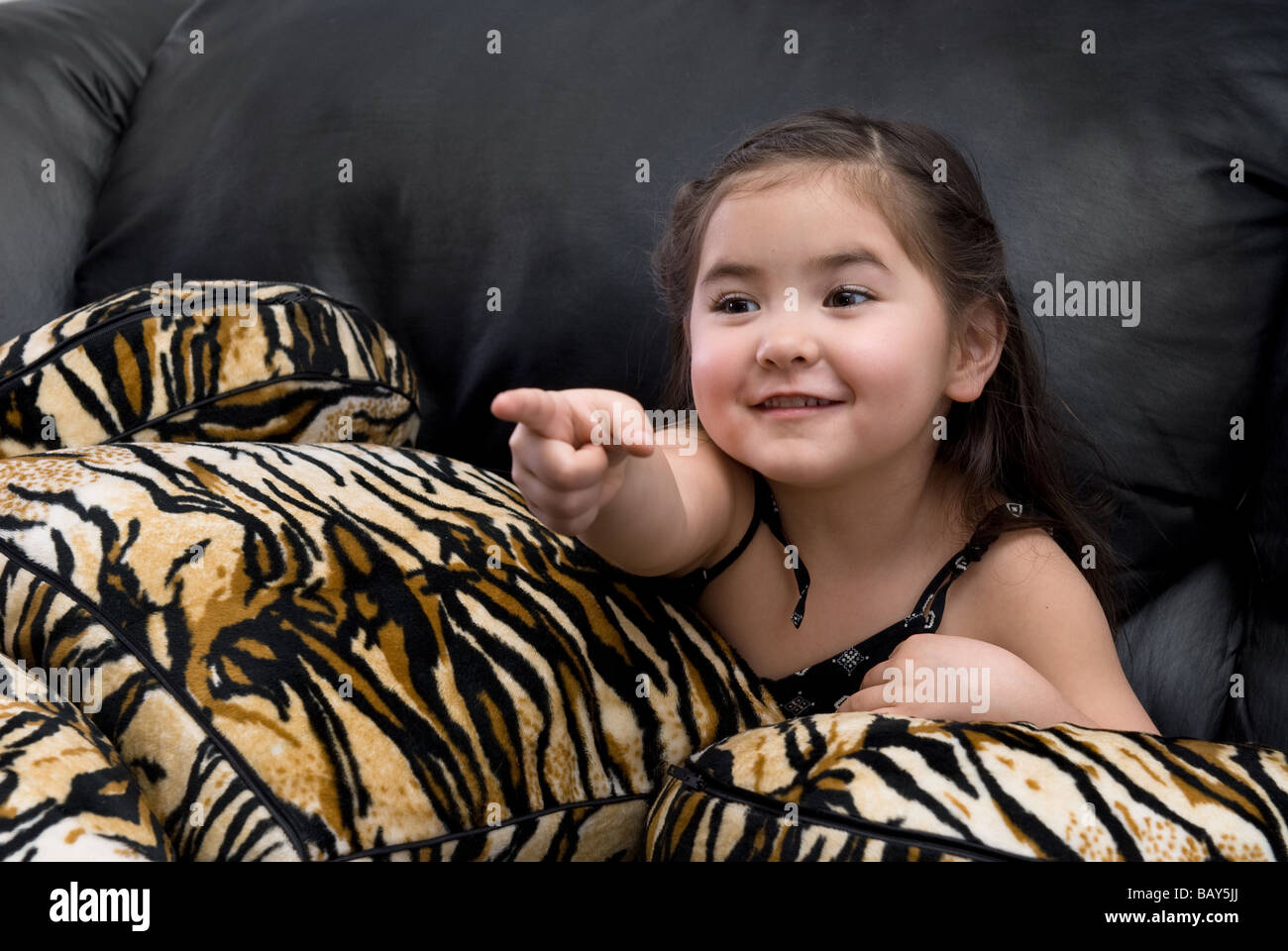 A smiling excited little girl eagerly points at something intriguing ...