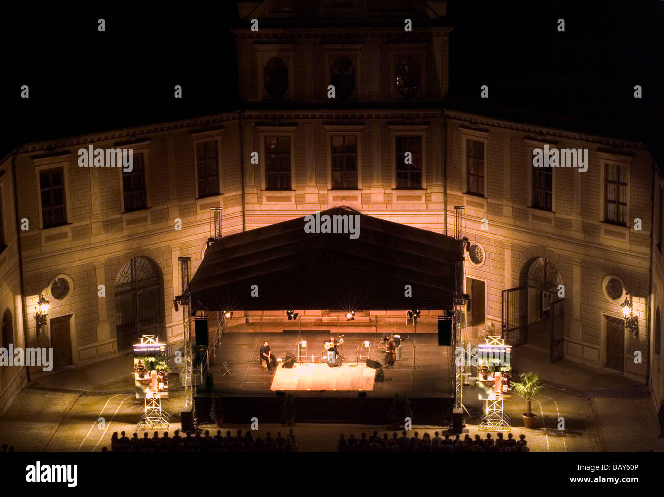 Musicians sitting on an illuminated stage at the courtyard of the ...