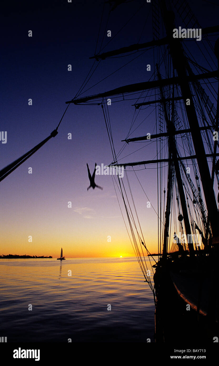 Man jumping from the mast of a sailing ship at sunset, Bora Bora ...