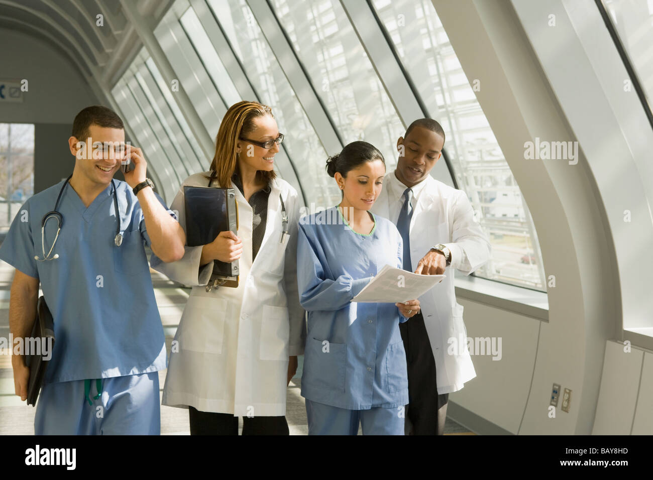 Multi-ethnic doctors and nurses reviewing paperwork in corridor Stock ...