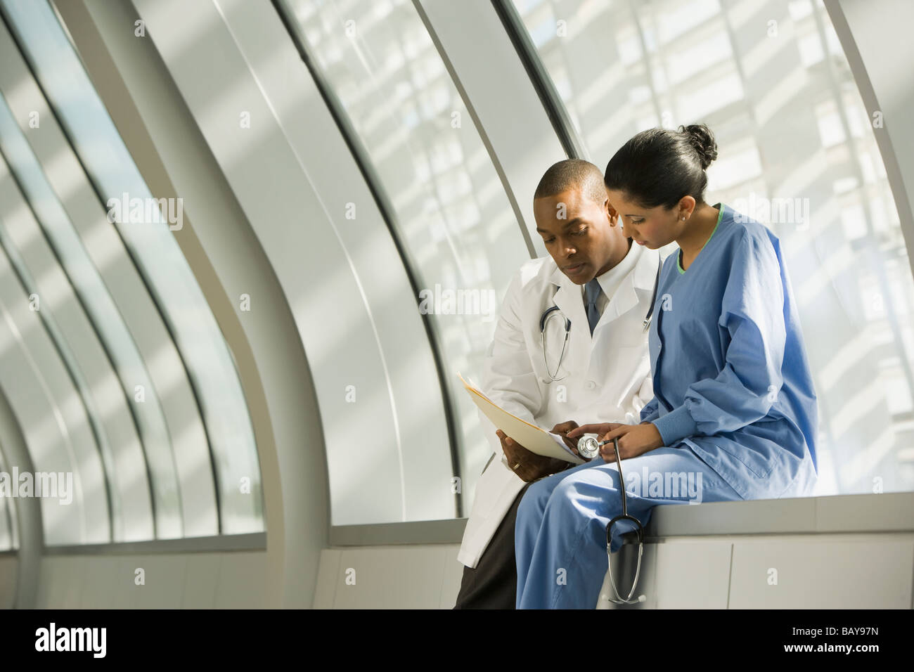 Doctor and nurse reviewing medical chart in corridor Stock Photo - Alamy