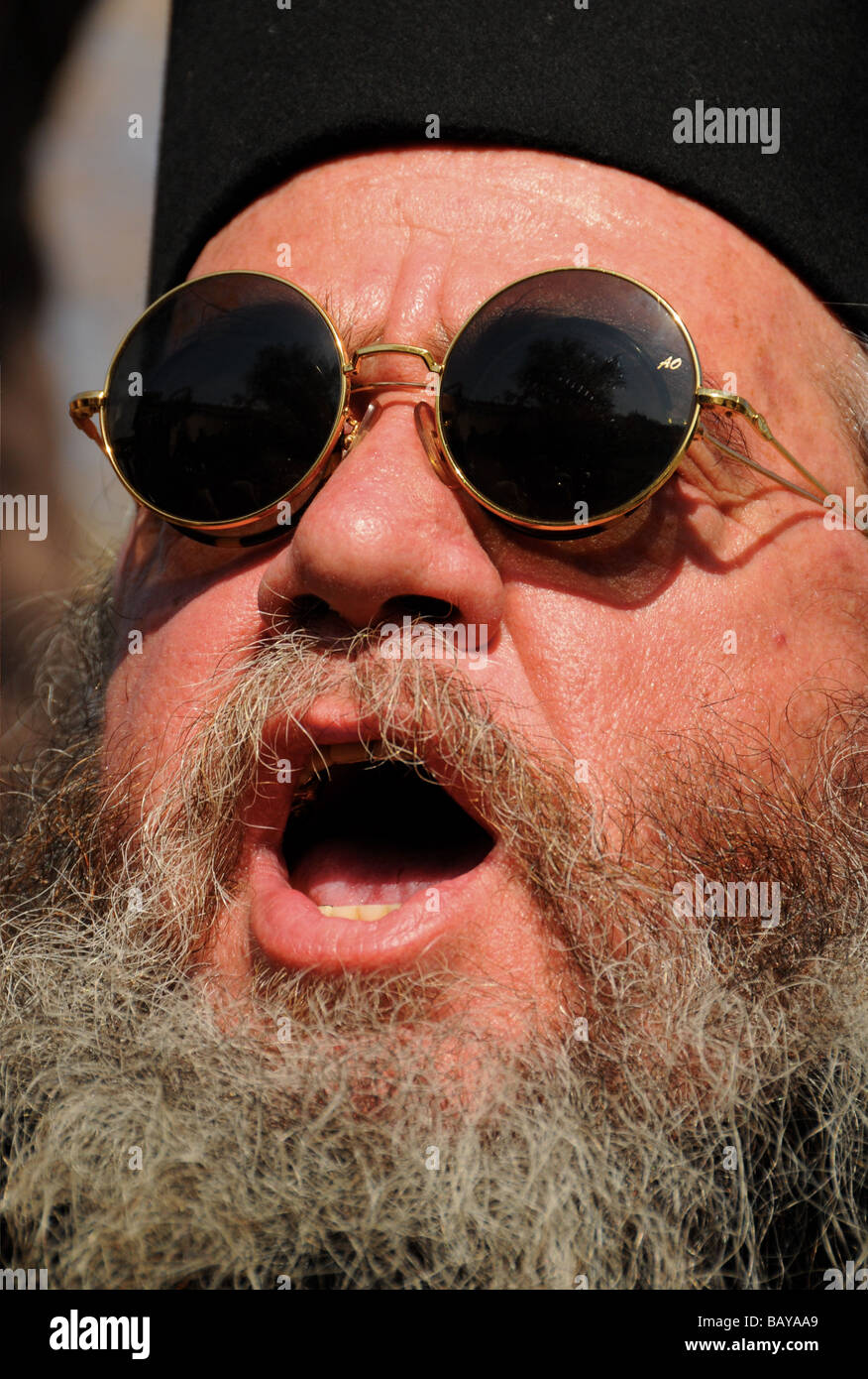 A Greek Orthodox Priest, wearing sunglasses. Pictured at a mass baptism ...