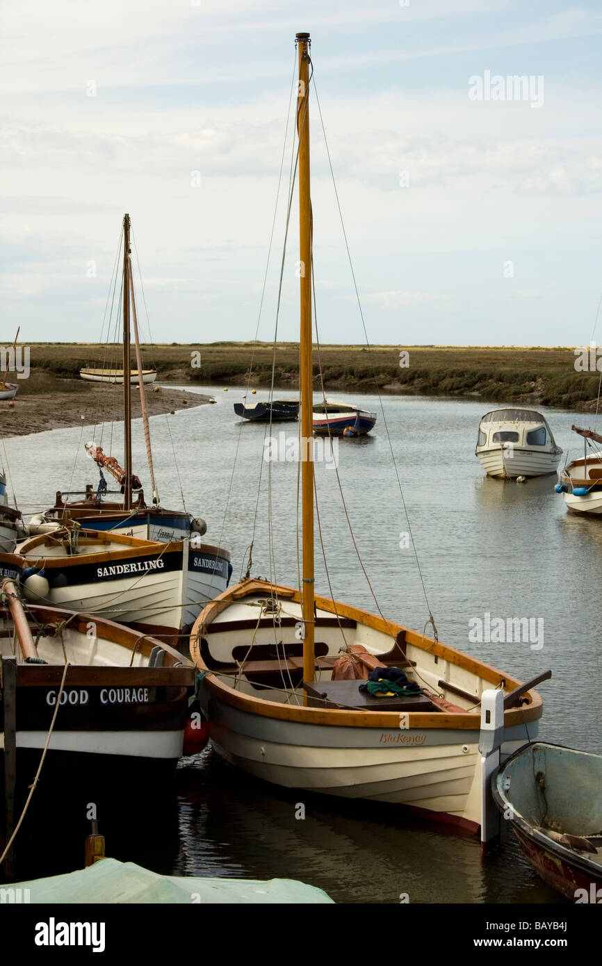 Small boats alongside quay in tidal creek, Blakeney, Norfolk, England ...