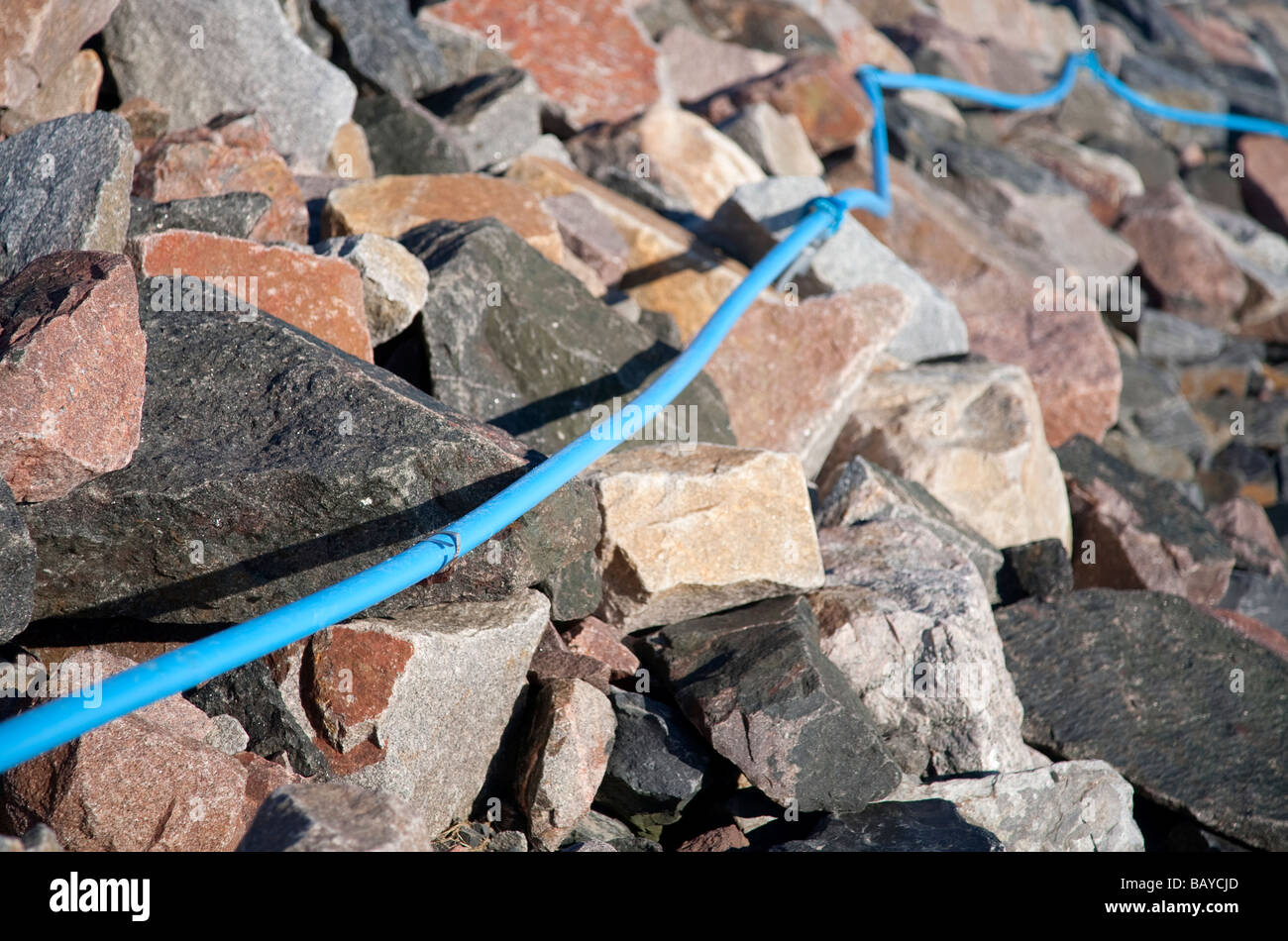 Surface mounted blue electrical cable on rocky terrain Stock Photo - Alamy