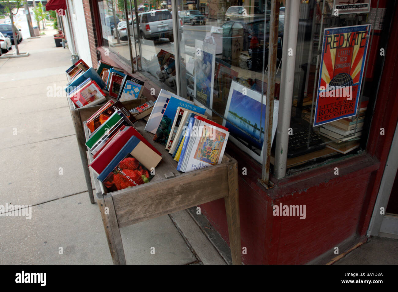 Books in rack on pavement at street bookseller's, a building with signs ...
