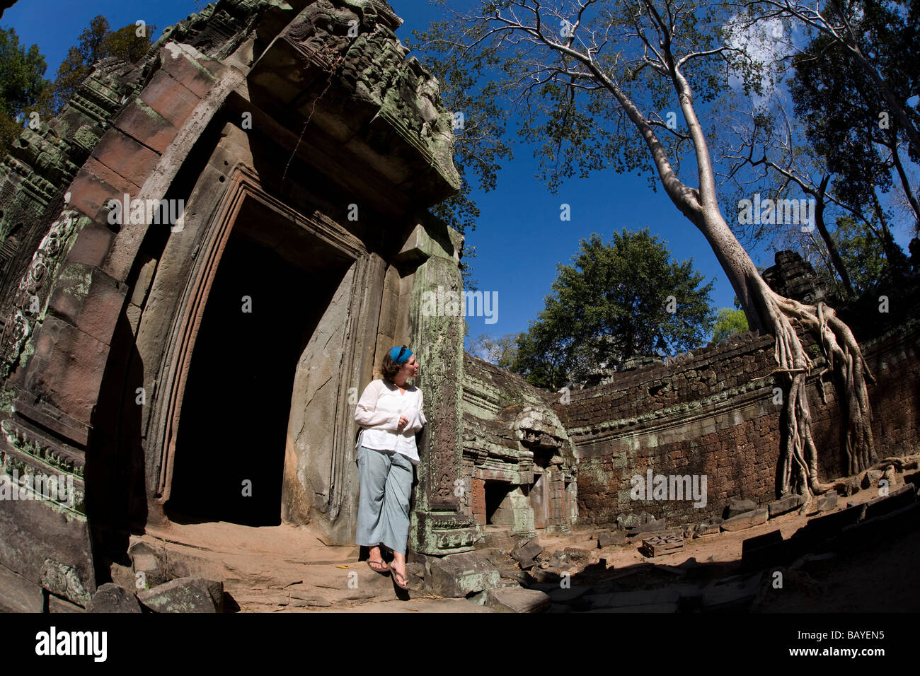 Tourist outside temple in ancient city of Angkor; Angkor Wat, Siem Reap ...