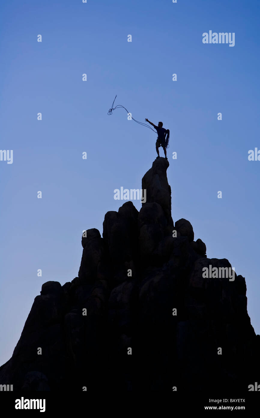A climber is silhouetted summitting a rock spire Stock Photo - Alamy