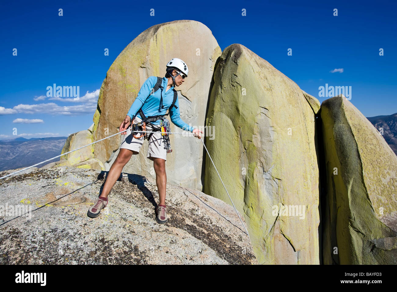 Climber beginning her descent from the summit of a rock spire Stock ...