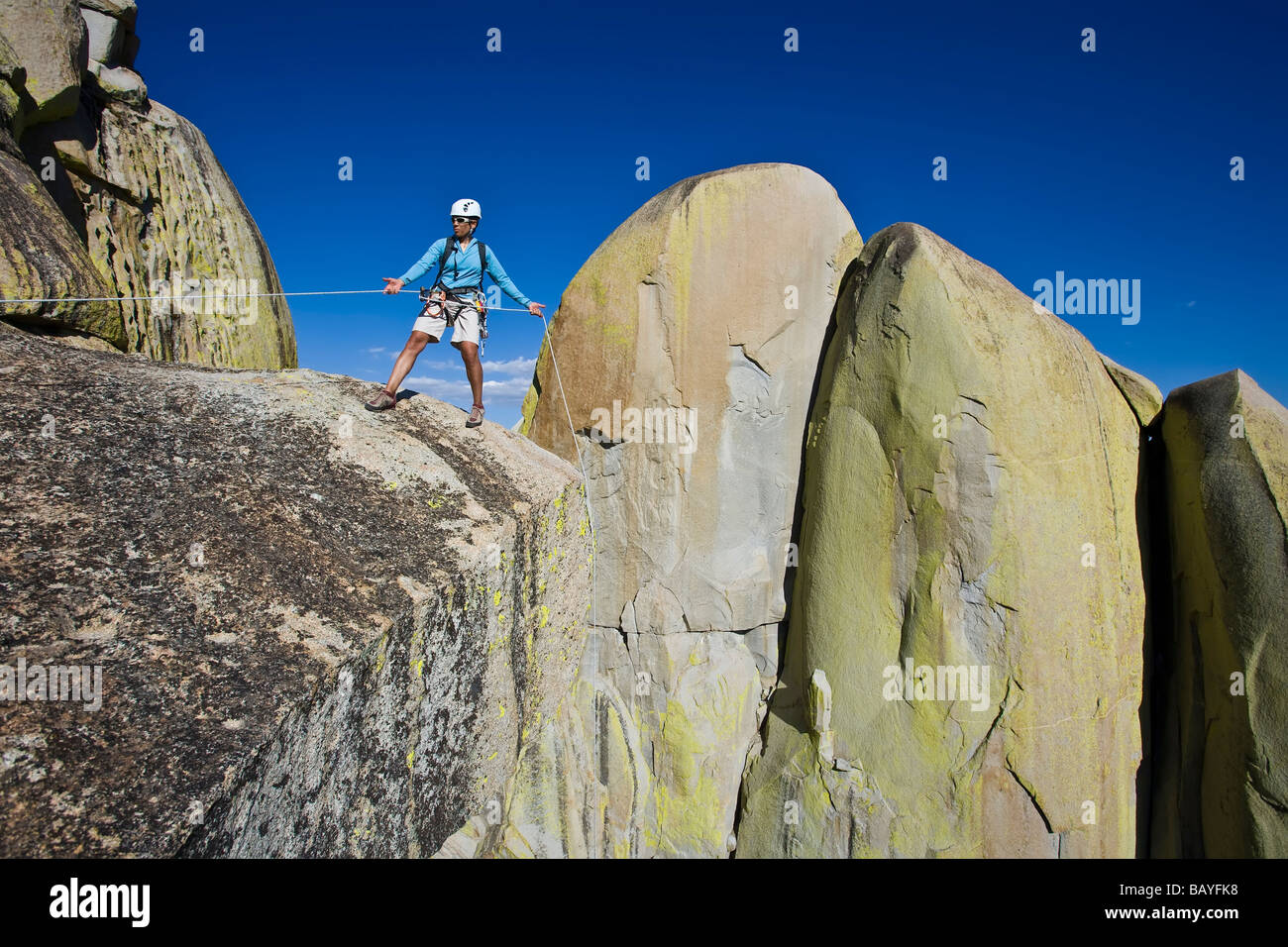 Climber beginning her descent from the summit of a rock spire Stock ...