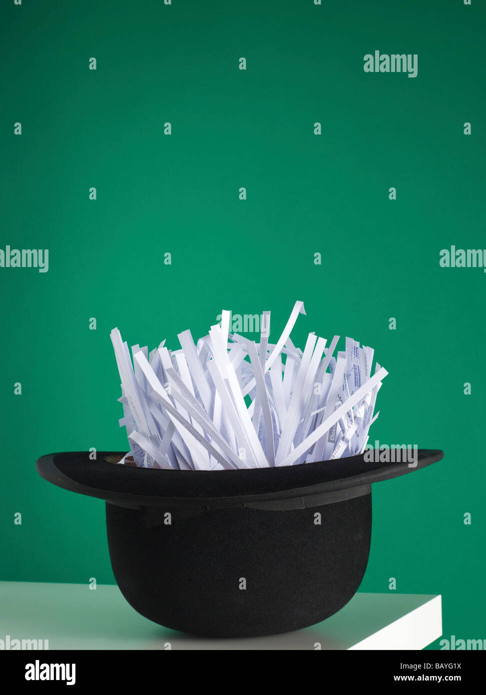 A bowler hat filled with paper shreddings against a green background in ...