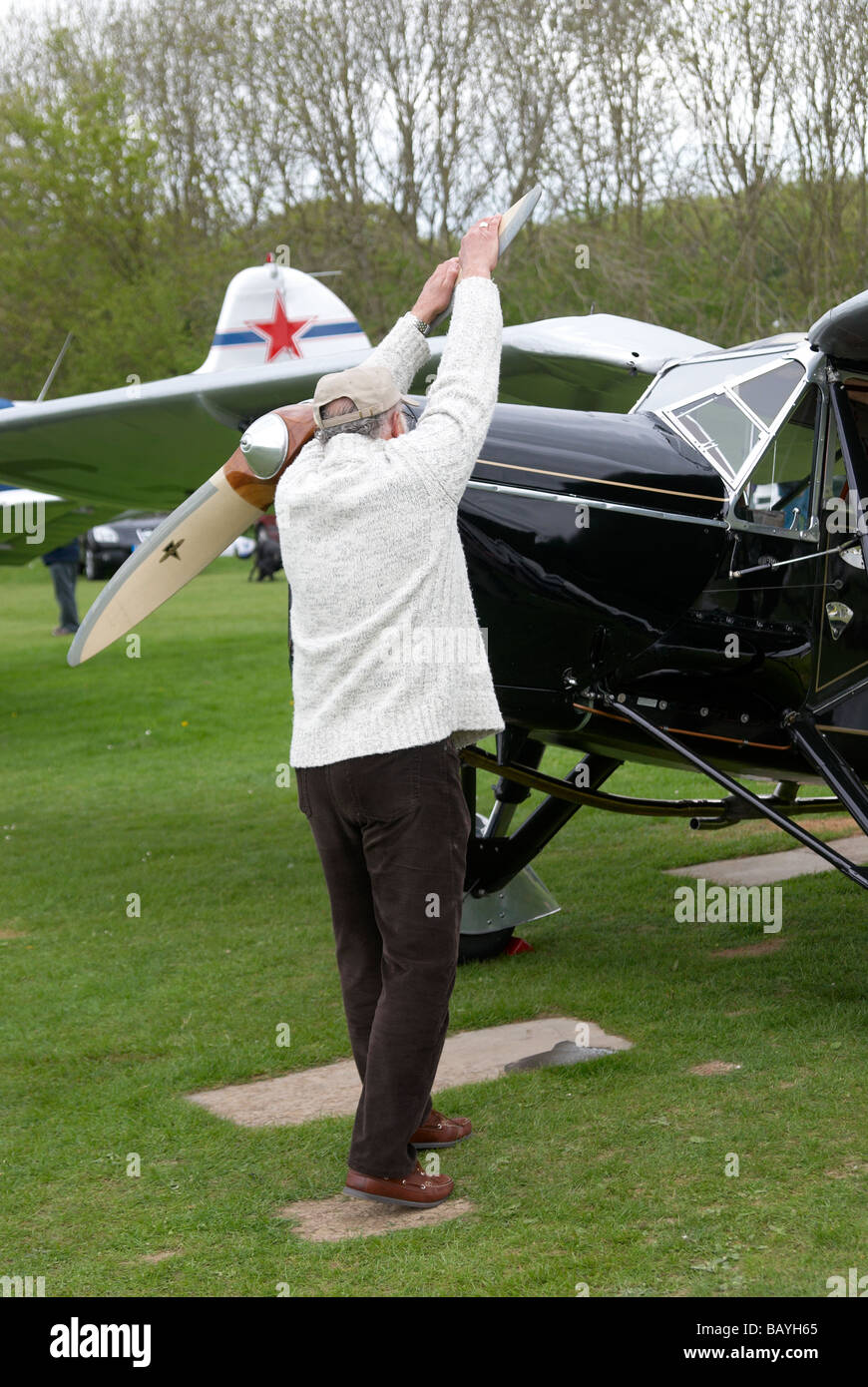 Preparing to swing the propeller to start the engine of a 1930's de ...