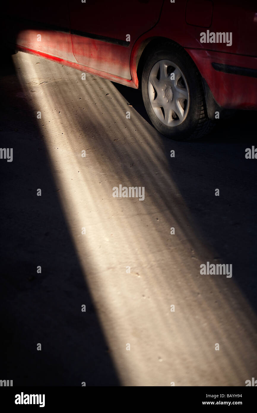 Dirty red car in the darkness revealed by beam of light Stock Photo - Alamy