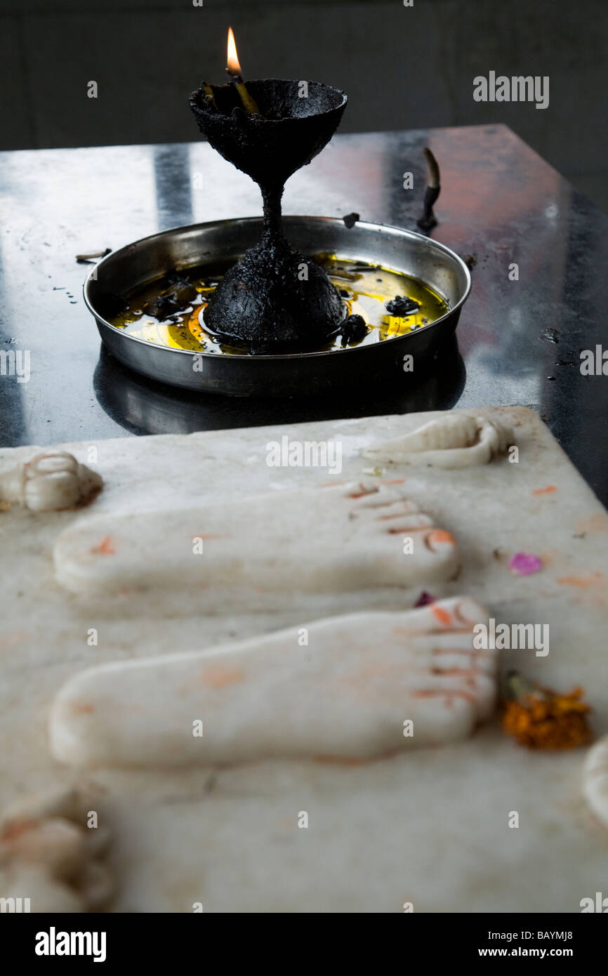Carving of feet in marble, alongside a butter-lamp, at the Jakhu Temple ...