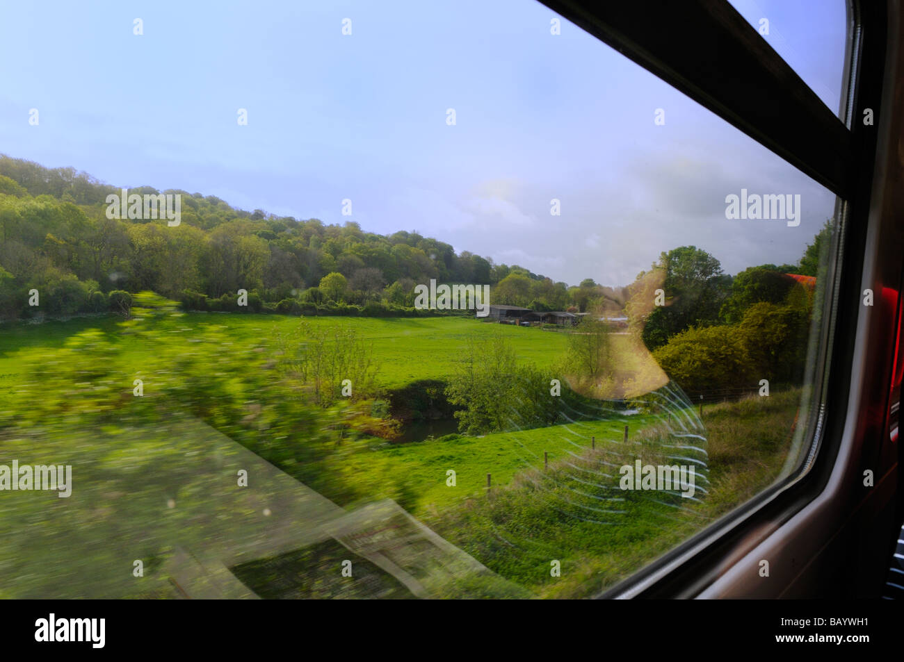 Passengers reflection in train window passing Wiltshire countryside ...