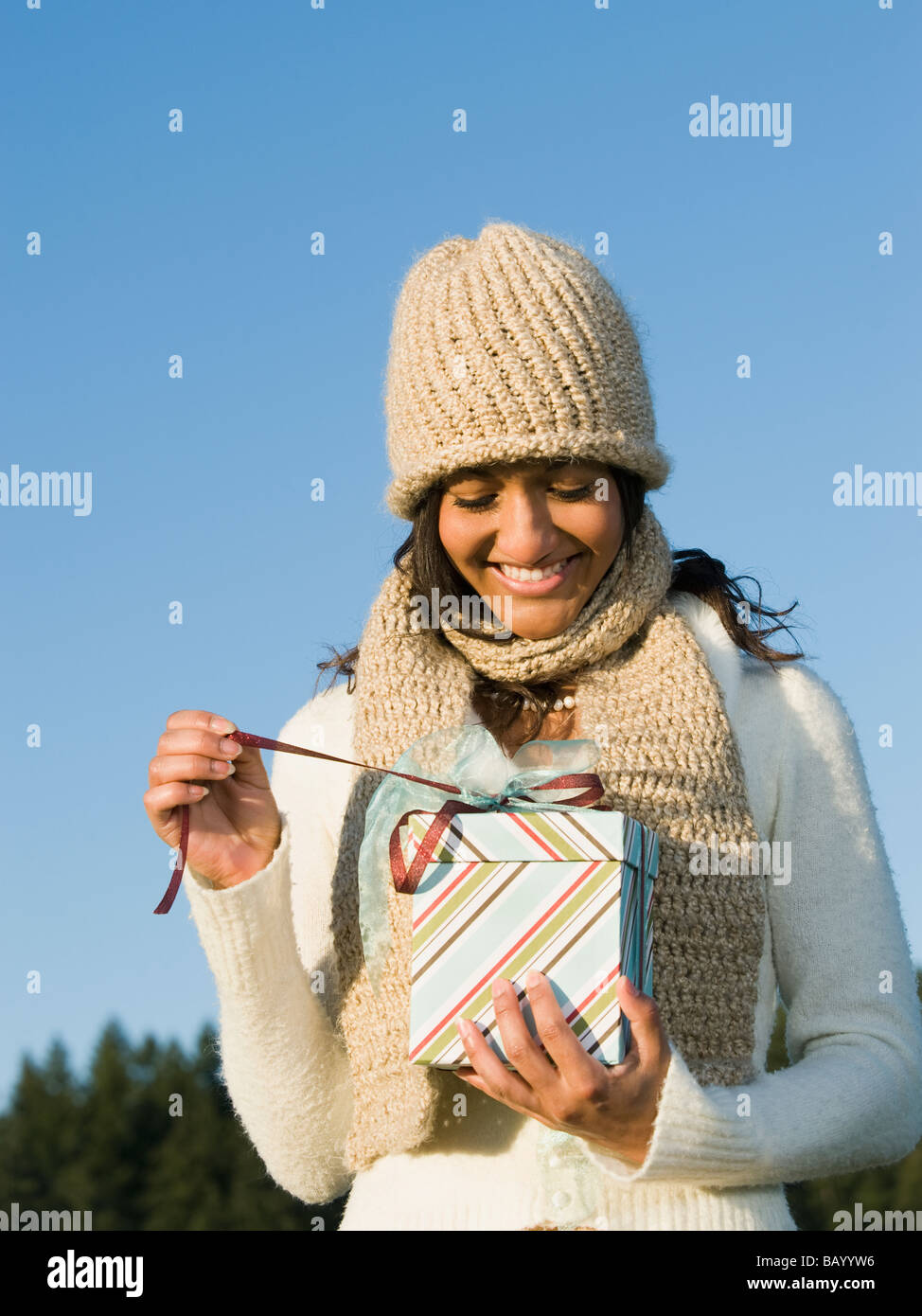 Mixed race woman opening gift Stock Photo - Alamy