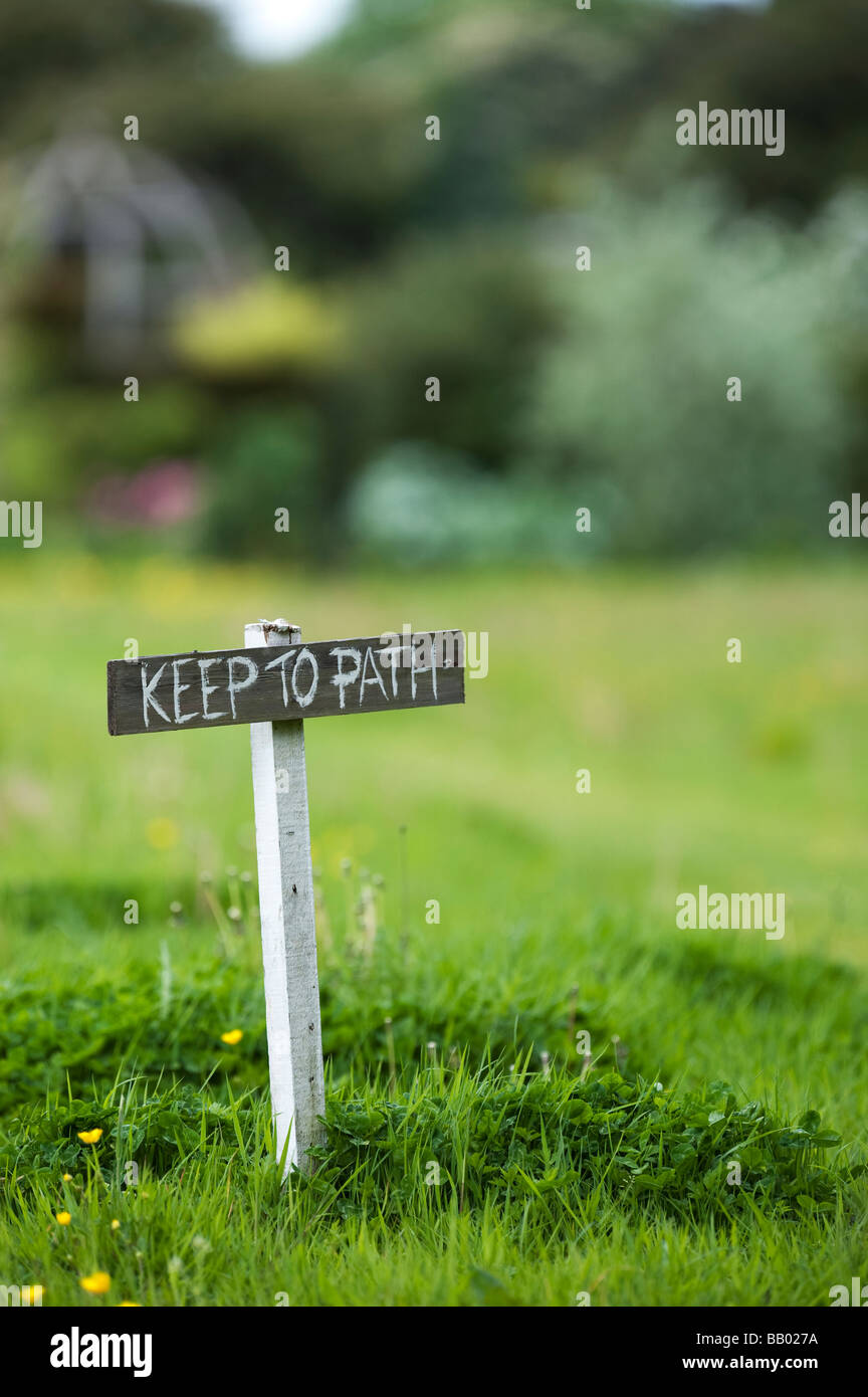 Keep to path warning sign in a garden through a wildflower meadow ...