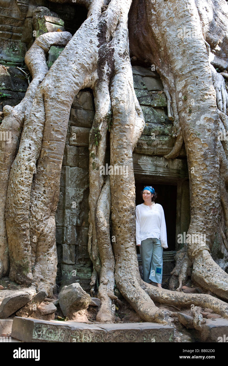 Tourist outside temple entrance overgrown with gigantic tree roots in ...