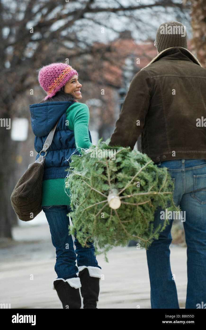 Couple carrying Christmas tree Stock Photo - Alamy