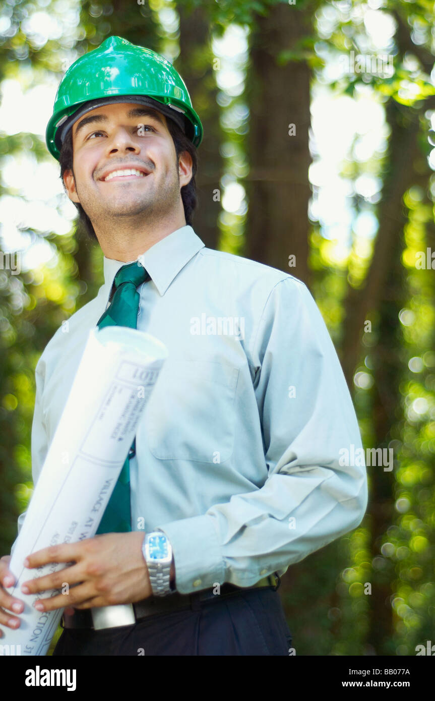 Hispanic architect holding blueprint and wearing green hard hat Stock ...