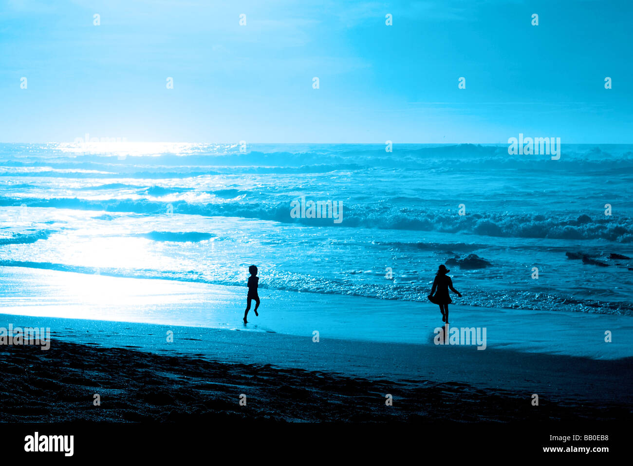 running children on evening ocean beach in blue Stock Photo - Alamy