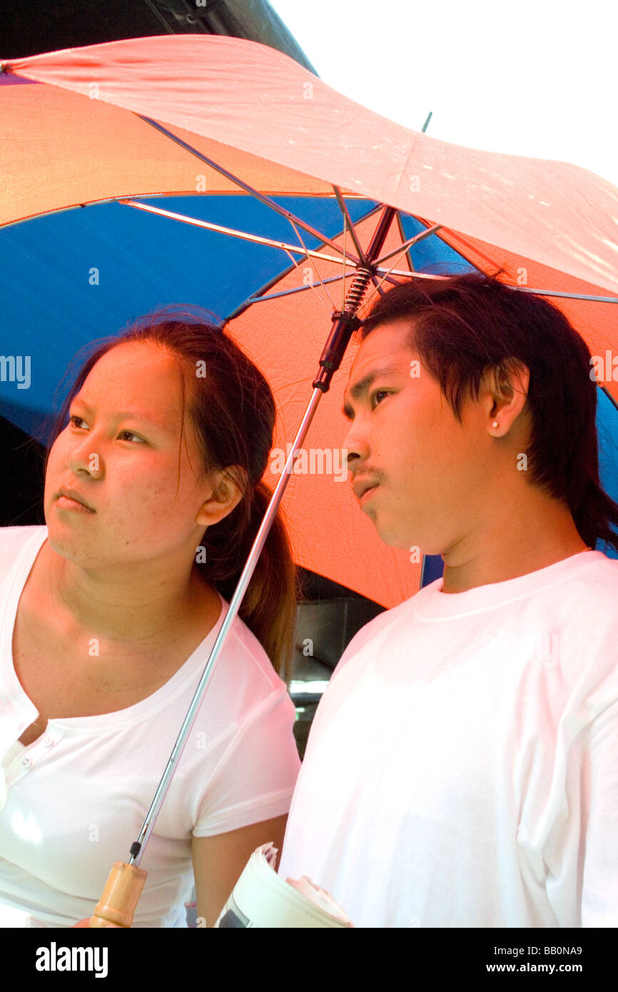Hmong couple under umbrella protecting them from intense sun rays ...