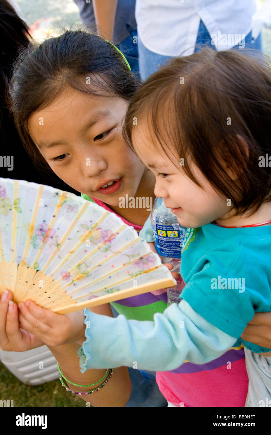 Hmong mom showing daughter the intricacies of a folding Hmong fan ...