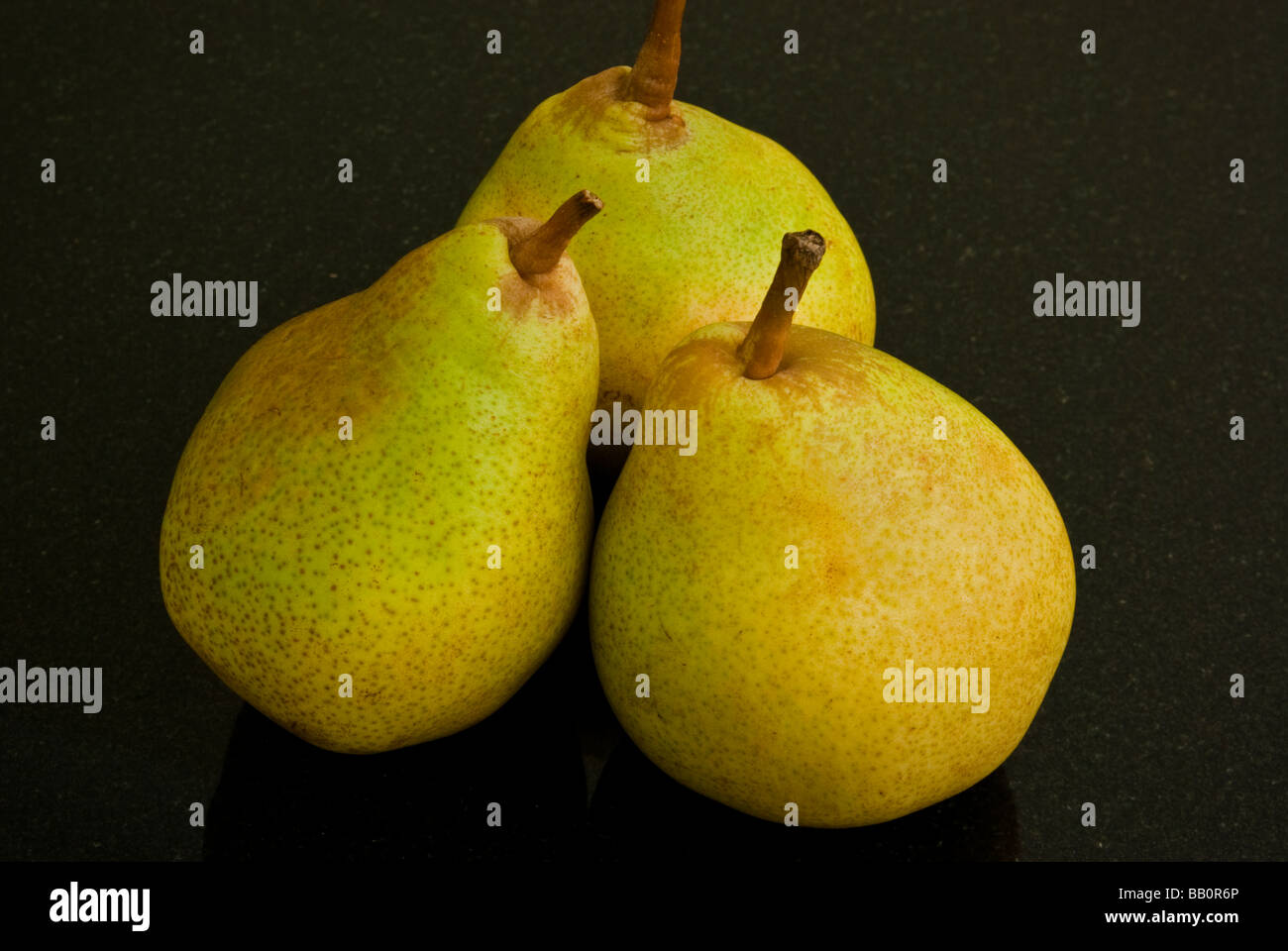 Still life of three Comice pears on a black granite background Stock ...
