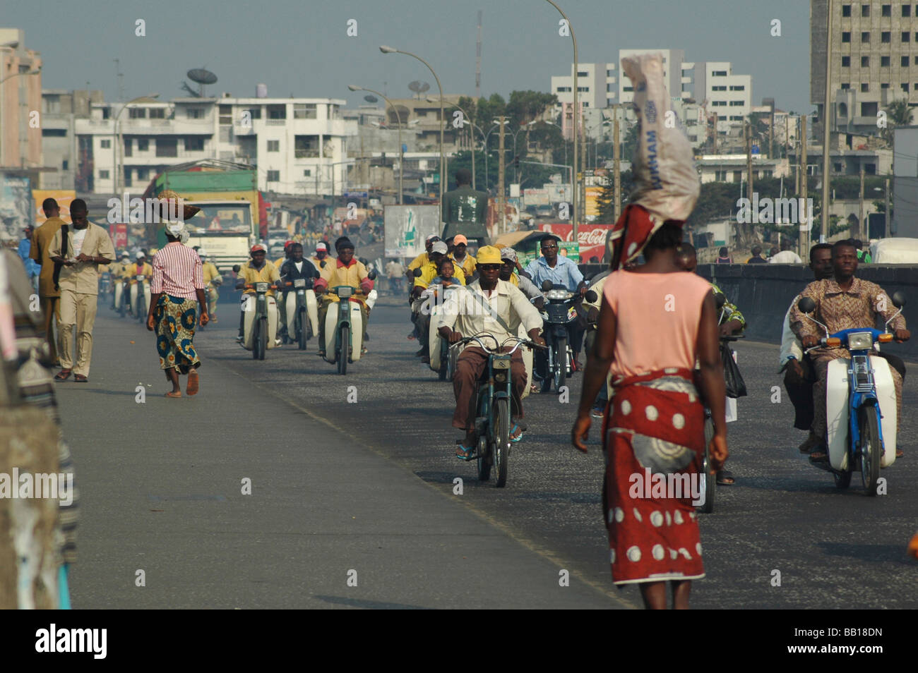 Benin, Cotonou. People walking on the street among motorbikes and cars ...