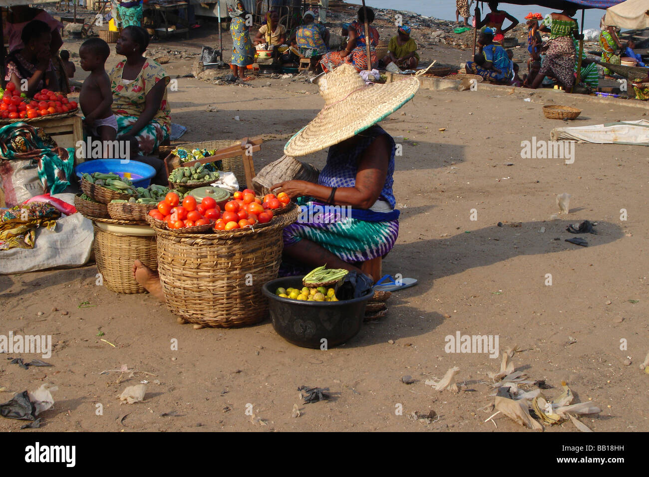 Benin, Cotonou. Woman with a big hat selling tomatoes in the market ...