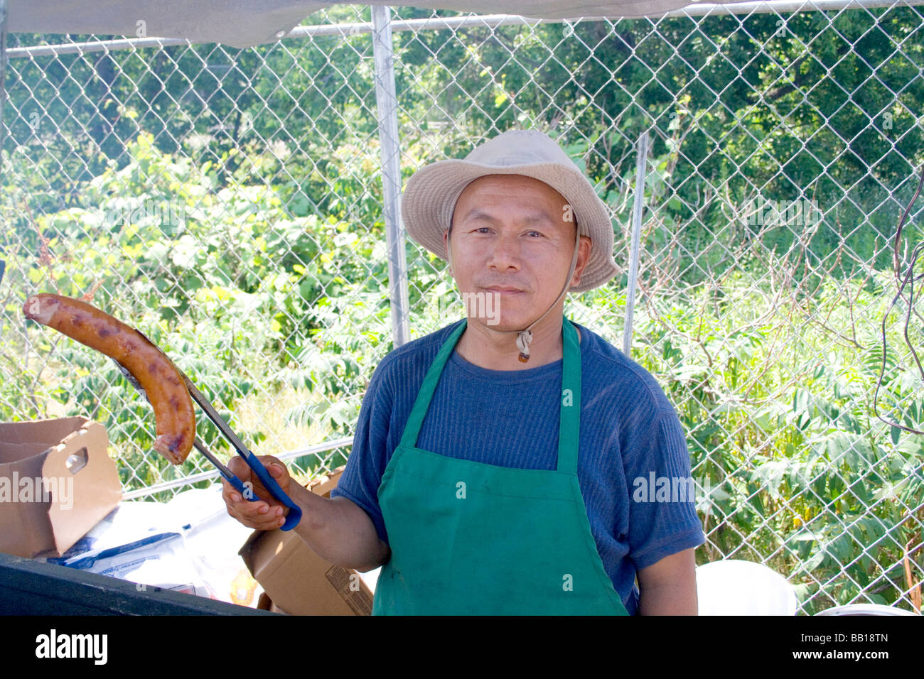 Hmong chef in the process of roasting rather large sausages. Hmong ...