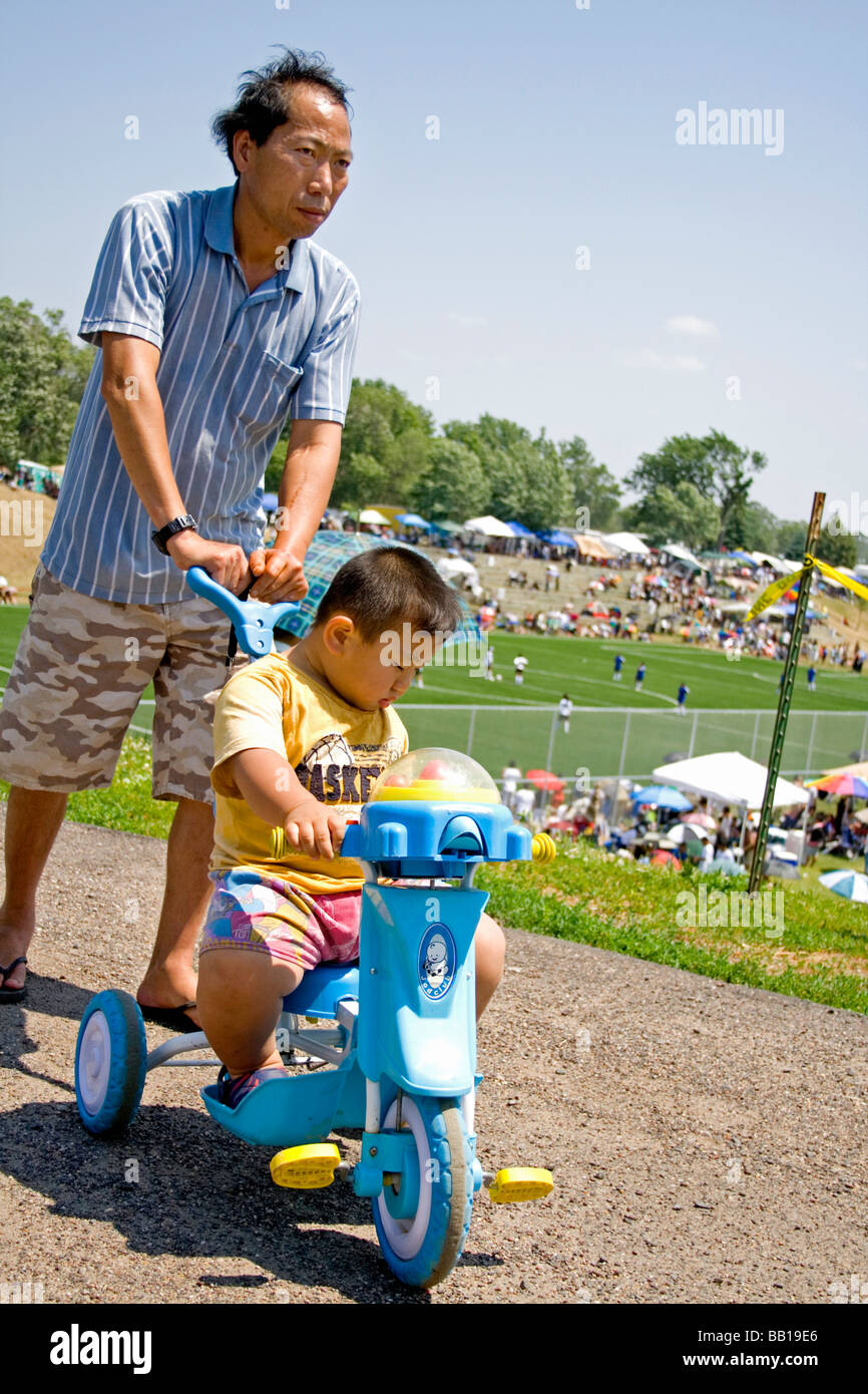 Hmong Asian father pushing son around soccer field during a game. Hmong ...