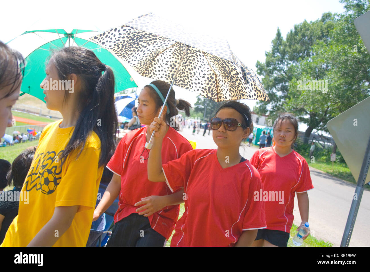Teenage Hmong SE Asian girls arrive soccer tournament sun umbrellas ...