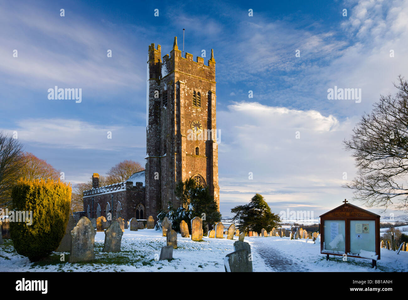 St Mary's Church Morchard Bishop bathed in afternoon sunshine on a snowy winter afternoon ...