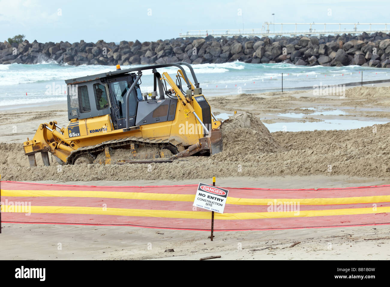 Earthmoving bulldozer moving sand to prevent beach erosion Stock Photo ...